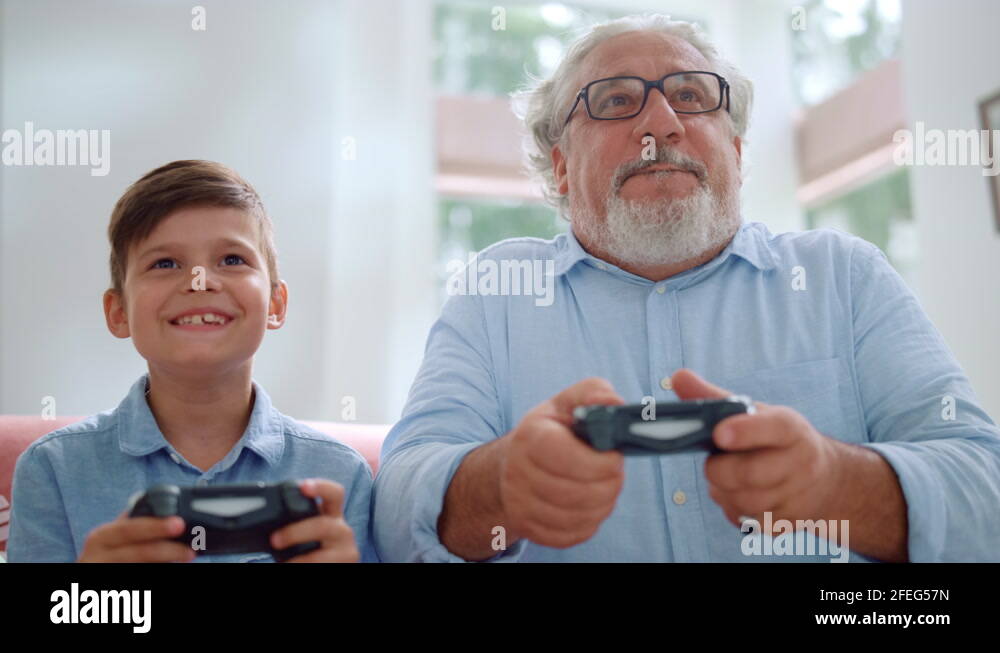 Grandfather playing video game with grandson. Mature man and boy using ...