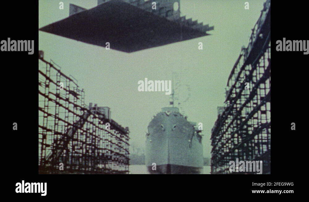 1940s: Newly constructed ship slides down ramp into harbor. Workers and ...
