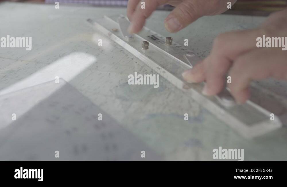 A captain is using a ruler to measure and calculate a navigation route ...