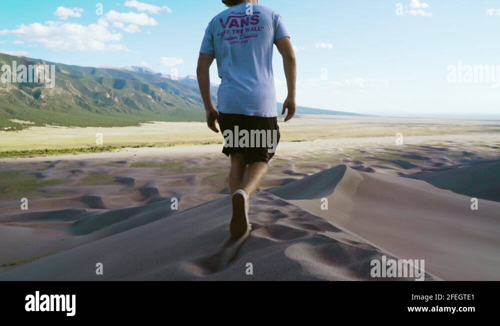 Man walking and lifting sand in The great sand dunes national park ...