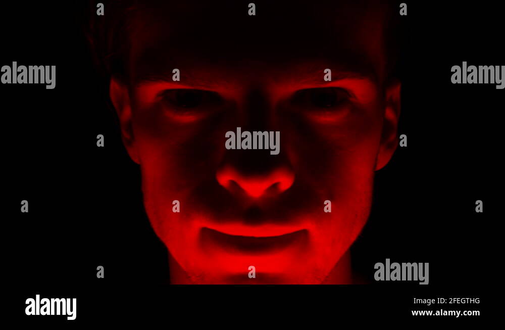 A scary and evil criminal man attacking a victim with a crazy smile and ...