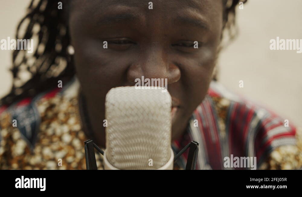 Close up of an African Man in Traditional shirt singing into a ...