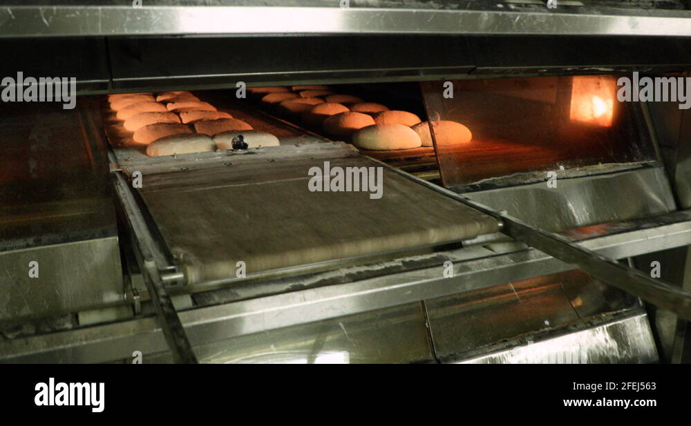 A Baker Manually Pulling The Deck Oven Loader, Moving The Raw Bread ...