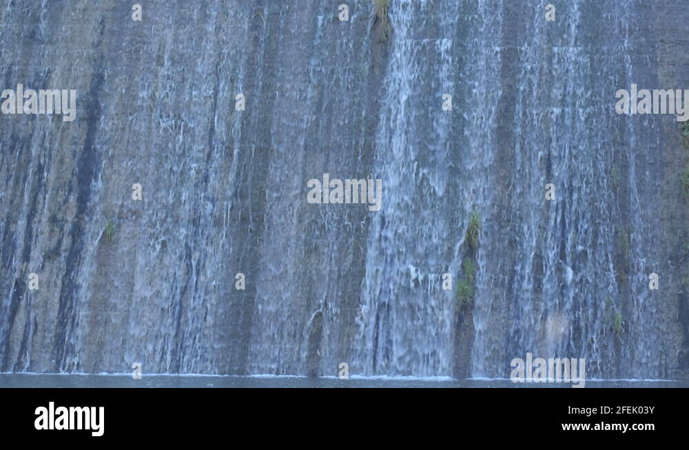 Water falling in a wall waterfall into a dam in a swamp Stock Video ...