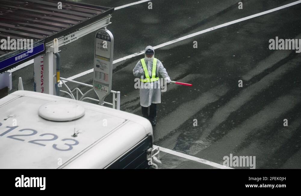 Japanese Traffic Guard Wearing Raincoat Stopping A Bus At The ...