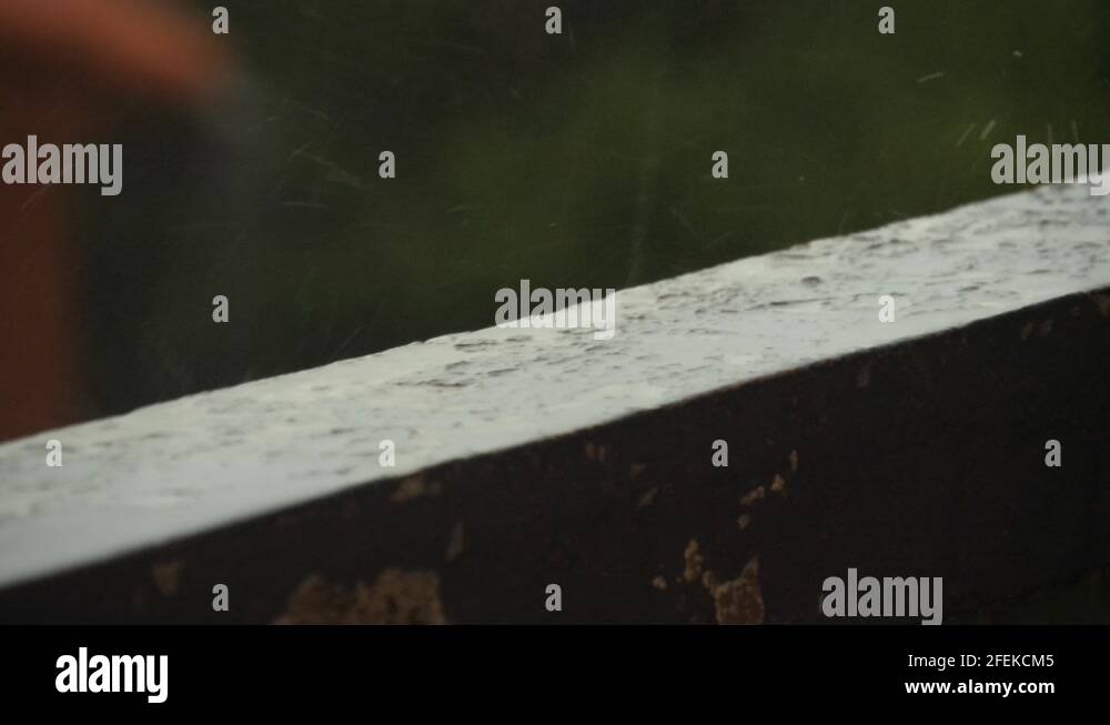 Tiny droplets of rain water falling in a splash on an old balcony wall ...