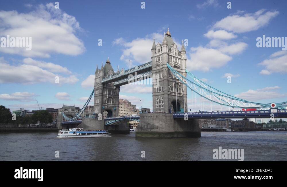 Traffic under and over Tower Bridge in London, boats, cars and people ...