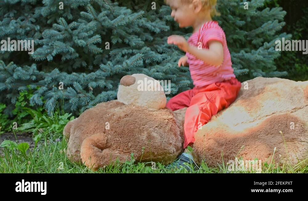Happy little child having fun jumping on his giant teddy bear Stock ...