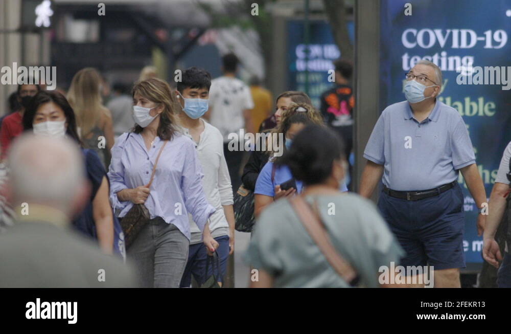 Crowd of people walking street wearing mask masks during coronavirus ...