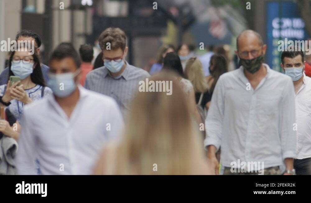 Crowd of people walking street wearing mask masks during coronavirus ...