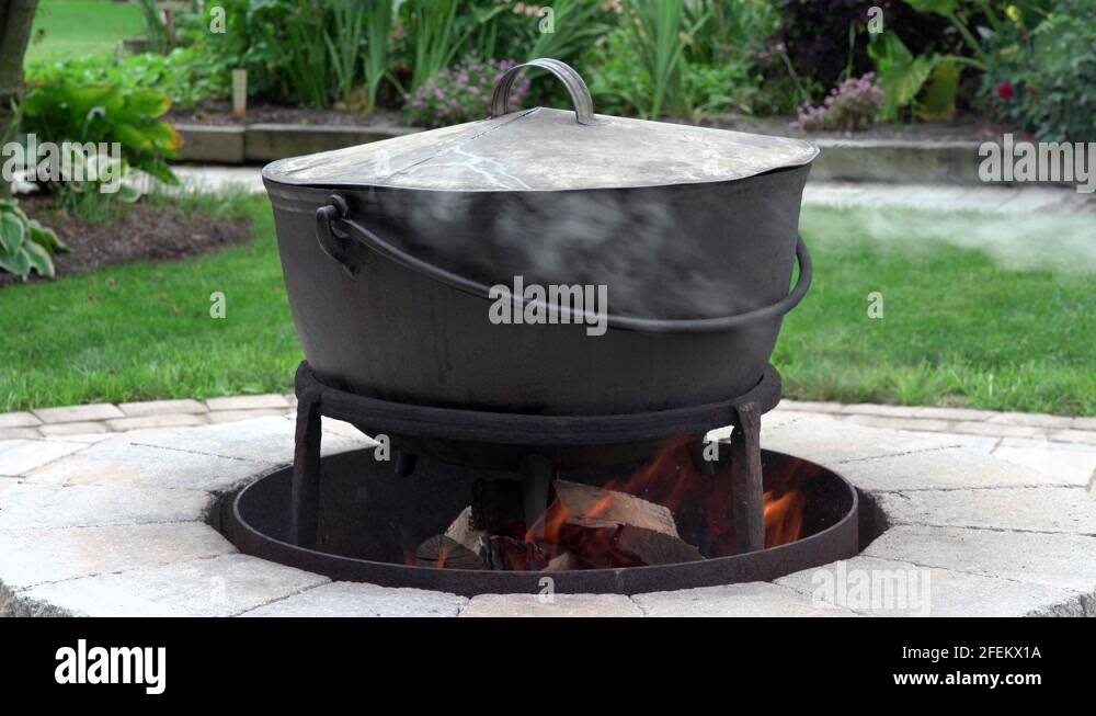 A fire burning in an outdoor fireplace and heating an old iron kettle ...
