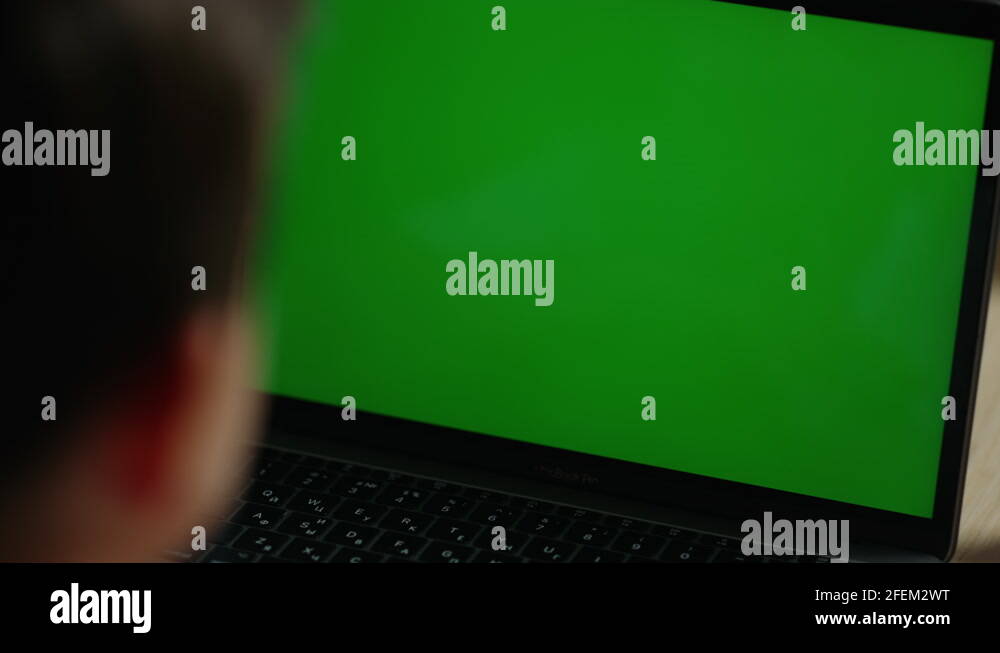 Boy using green screen computer. Schoolboy looking green screen netbook ...