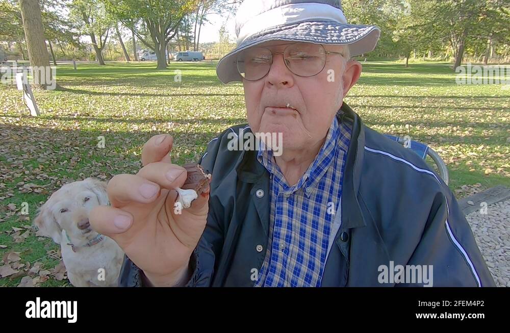 Older man enjoying eating a messy smore and wiping off chocolate on his ...