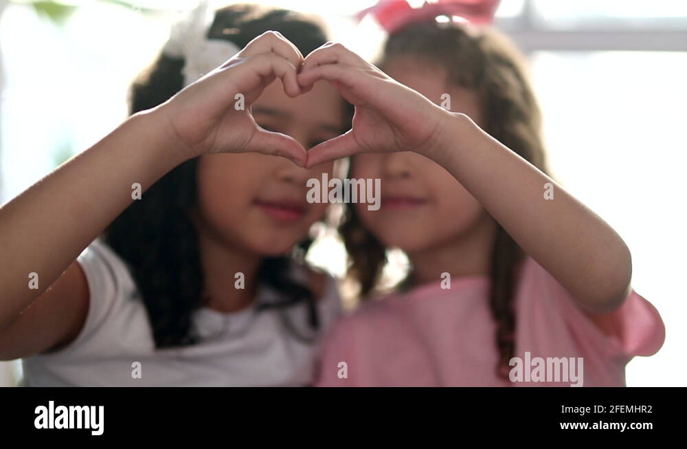Two little sisters making a heart sign together Stock Video Footage - Alamy