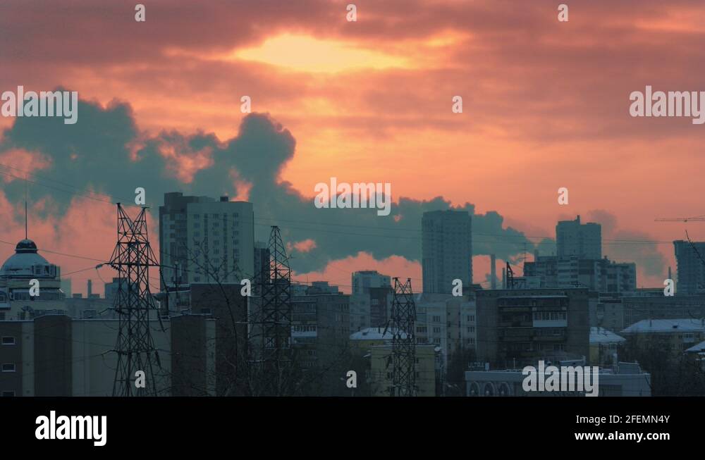 Smokestacks emitting smoke sunset sky over dark winter city skyline ...
