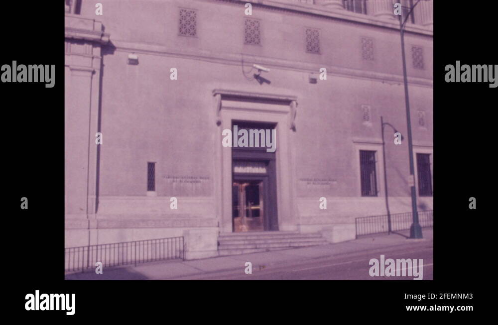 1970s: Outside of office building with security camera. Front of ...