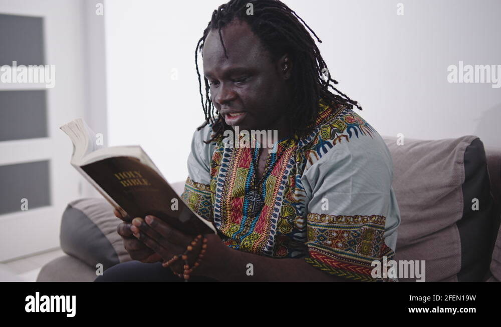 Christian black man reading aloud Holy Bible at home. Man of faith ...