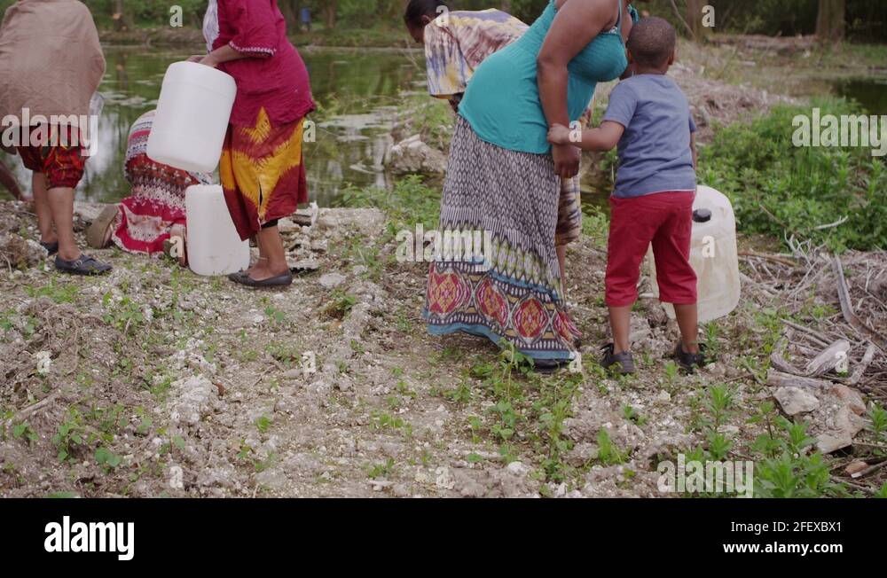 African villagers at river fill containers with as much water as they ...