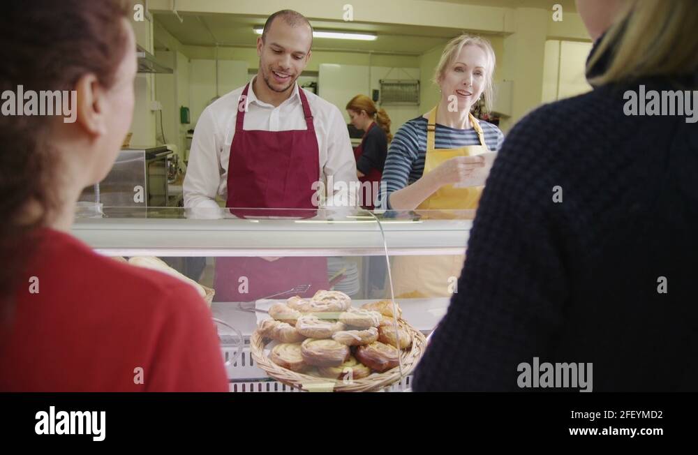 Friendly staff serving customers with a smile at the bakery counter ...
