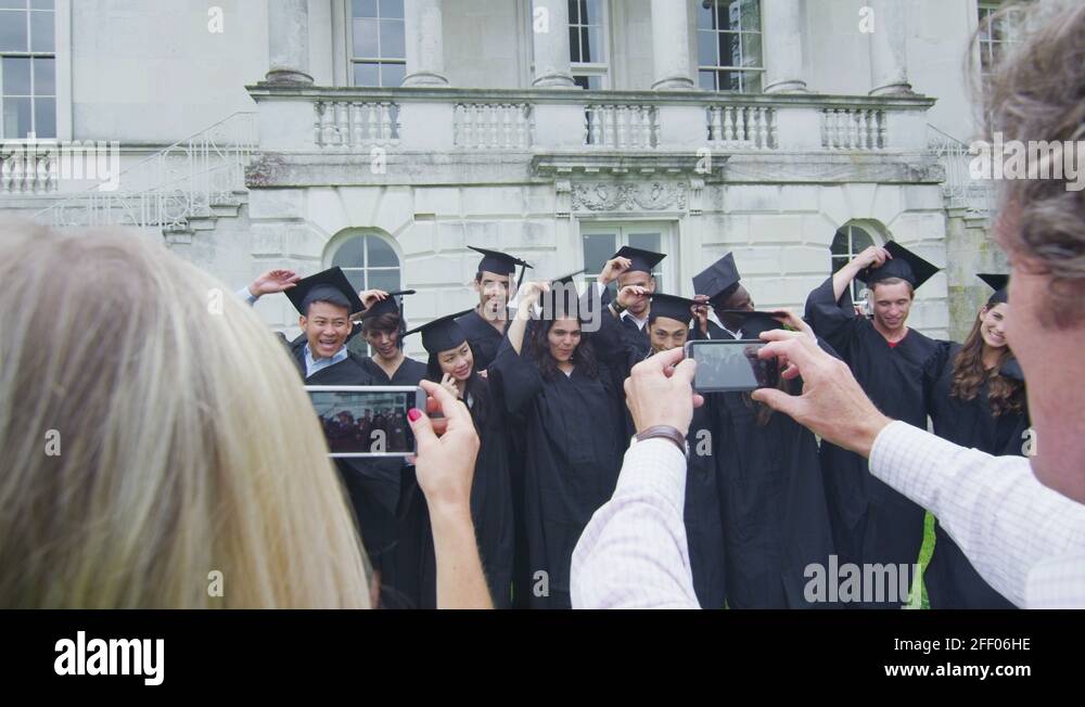 Happy students on graduation day stand in a line & pose for photographs ...