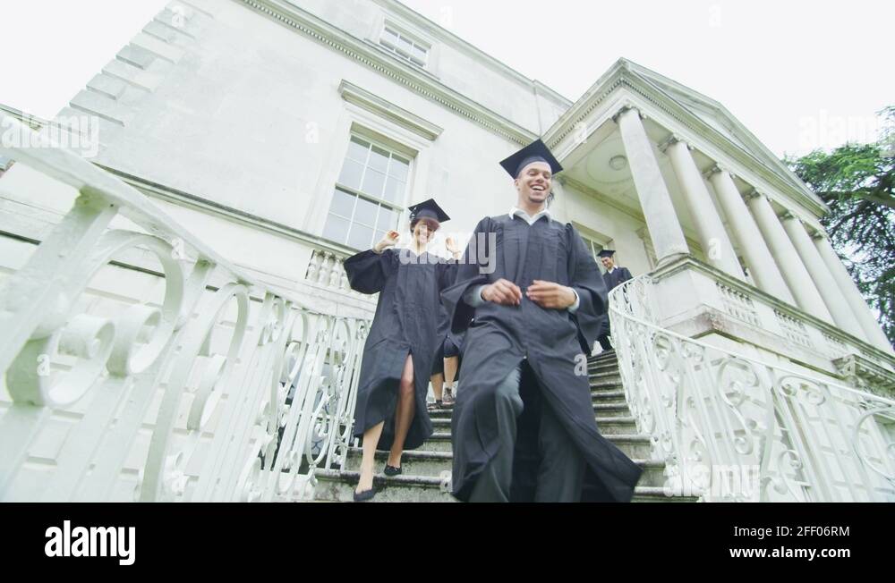 Excited students on graduation day run down a staircase outside college ...