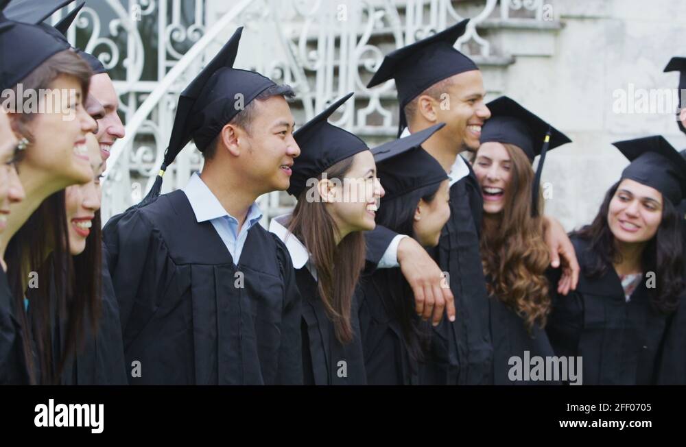 Happy students on graduation day stand in a line & pose for photographs ...