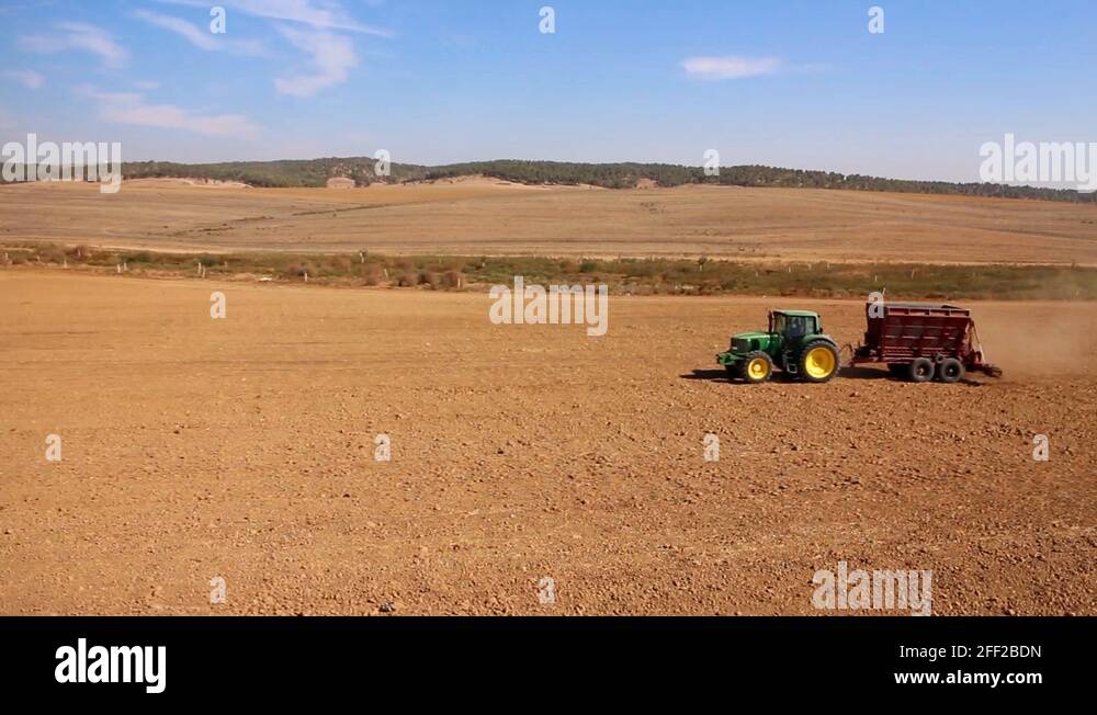 Tractor with a cart in the field spreader Fertilizer- side shot Stock ...