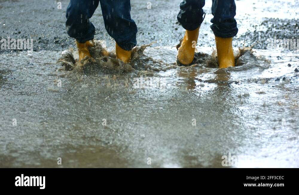Two young boys jumping in mud puddle Stock Video Footage - Alamy