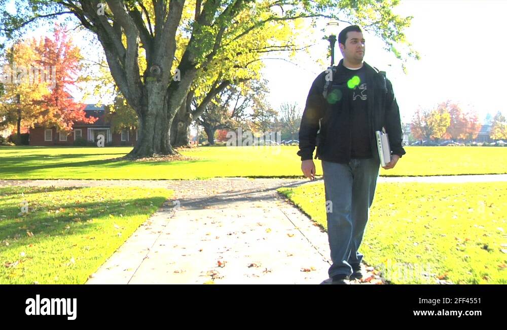 College student walking down sidewalk Stock Video Footage - Alamy