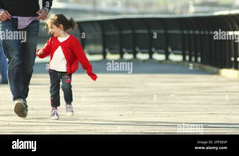 An excited little girl runs ahead of her dad on the board walk Stock ...