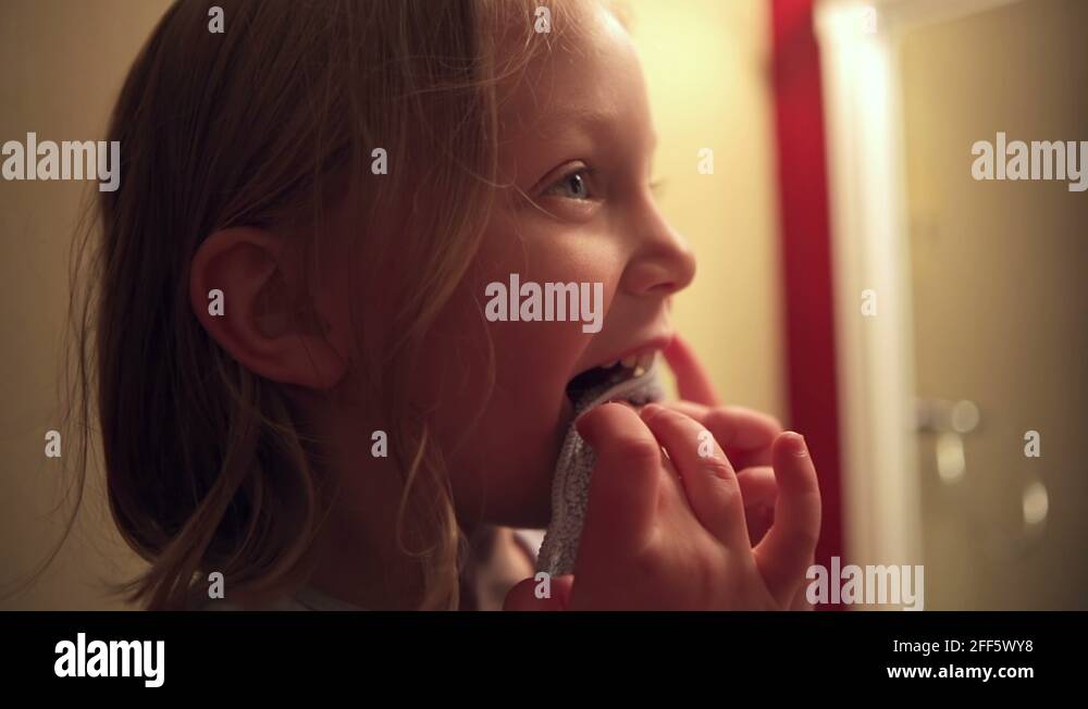 An adorable little girl hold a towel over the area where her tooth fell ...