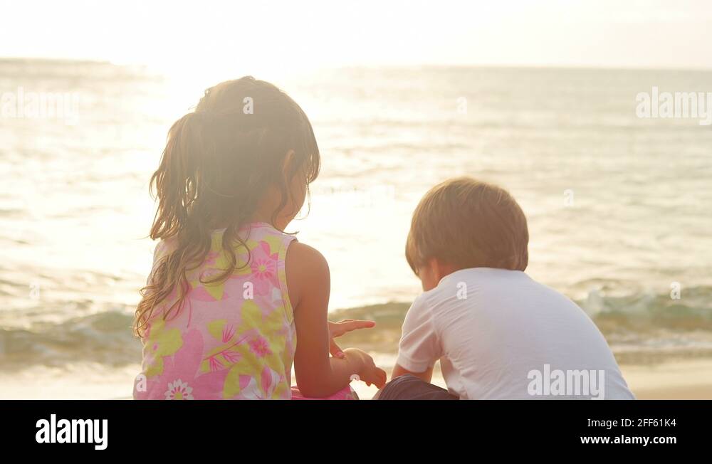 A Young Brother And Sister With Their Arm Around Each Other Sit On A