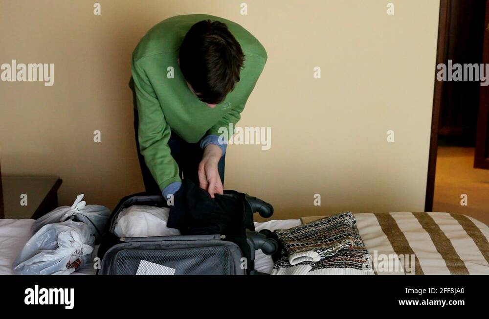Young man packing his luggage, teenage boy with suitcase in a hotel ...