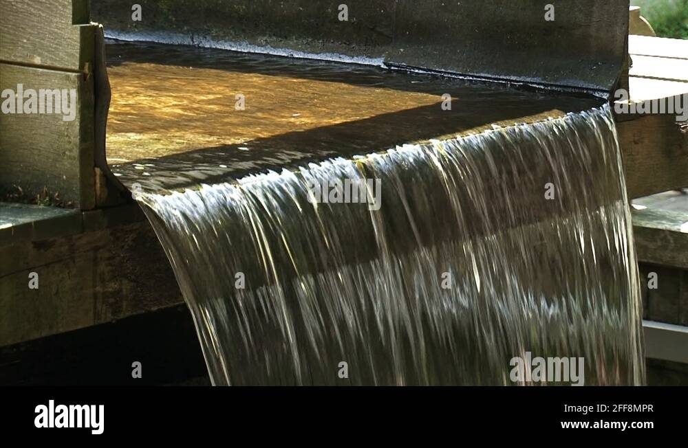 Water flow and falling water from wooden waterway to water wheel Stock ...