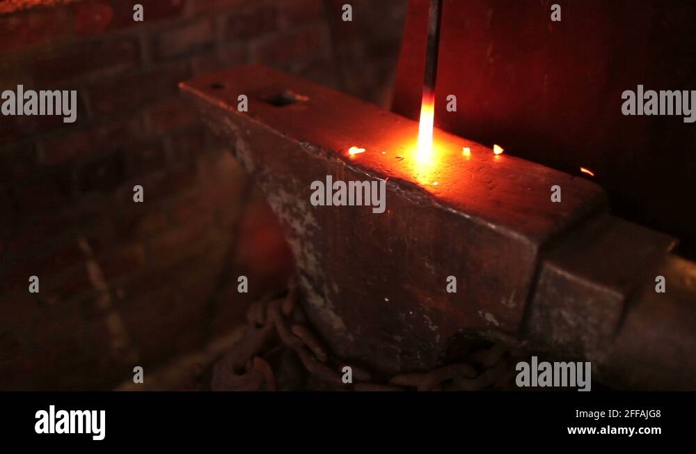 Blacksmith forging red hot iron rod on anvil, puts back in fire ...