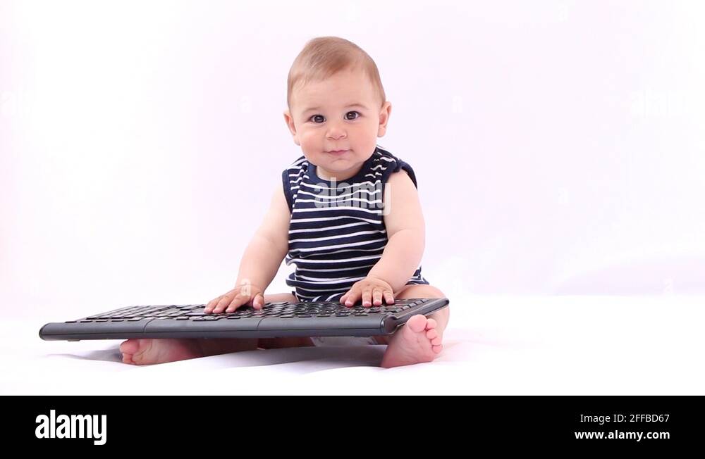 Hi Tech Baby. Boy playing with a computer keyboard against white ...