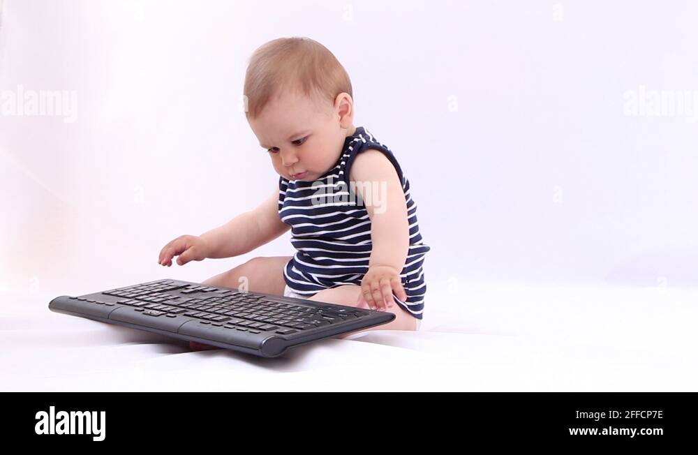 Hi Tech Baby. Boy playing with a computer keyboard against white ...