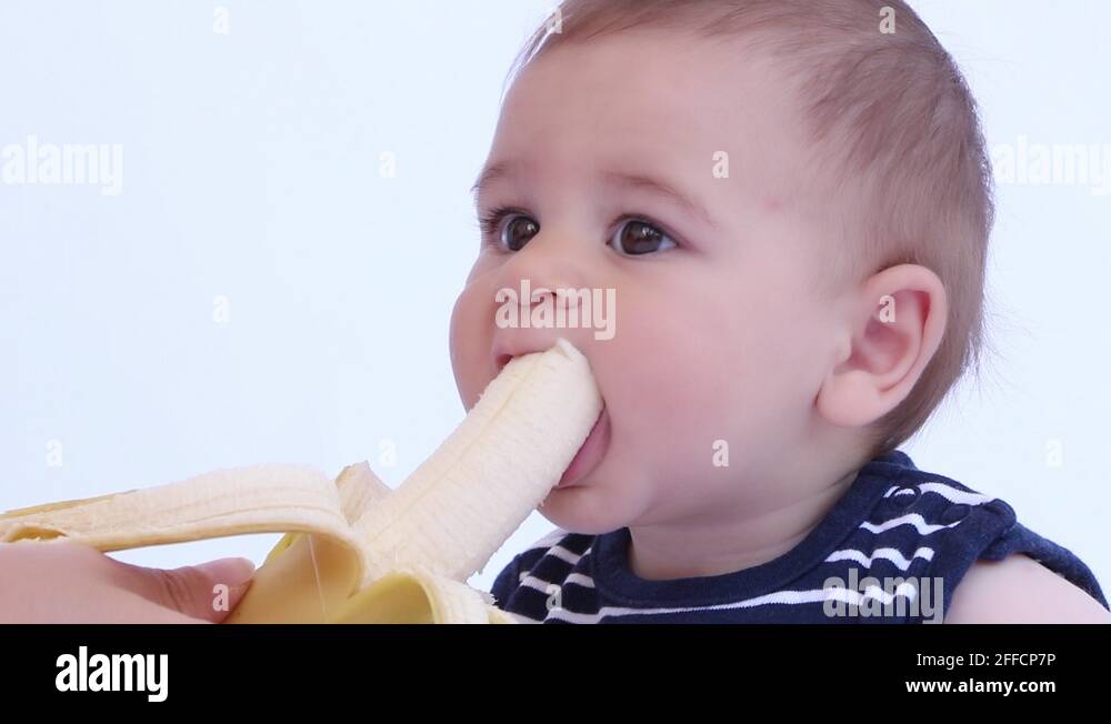 Baby boy is eating a banana on a white background Stock Video Footage ...