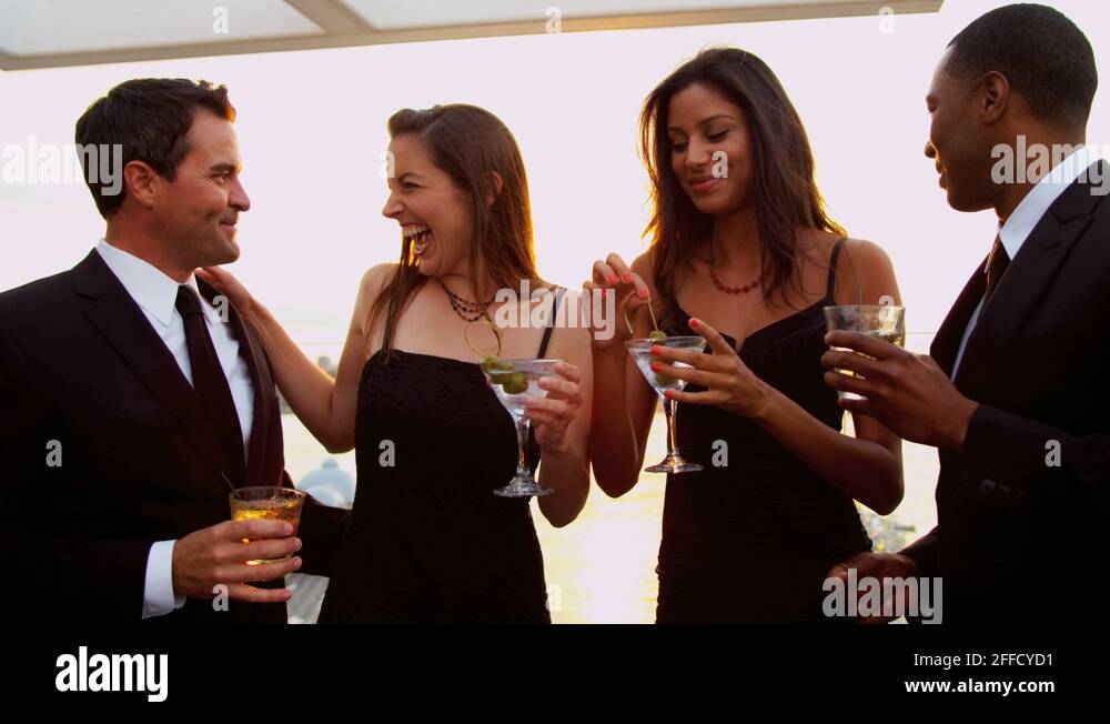 Multi ethnic couples drinking and gossiping at cocktail party sun lens ...