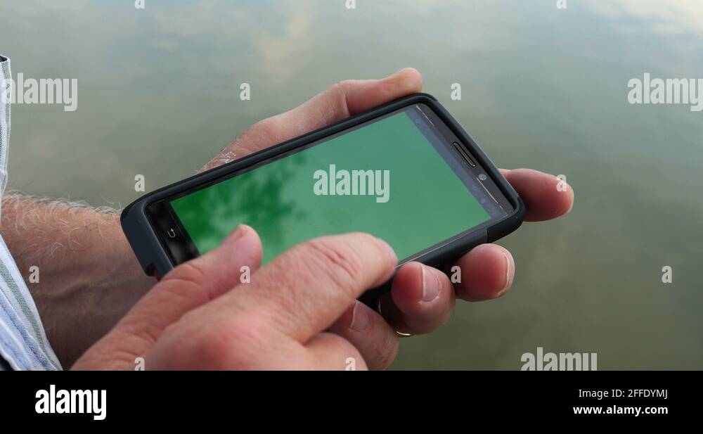 1881 Man Holding Smart Phone with Green Sceen next to Lake, 4K Stock ...