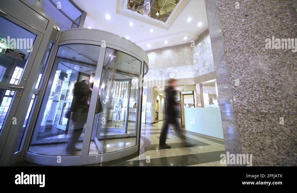 People walk through revolving entrance door into the building Stock ...