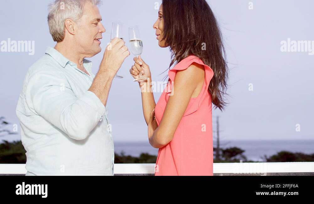 A man and woman cross arms and drink champagne on a windy deck Stock ...