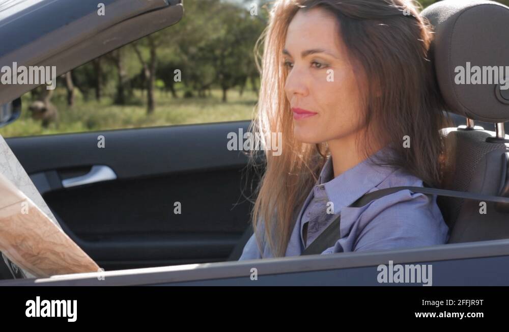 Woman in convertible car looking at a map Stock Video Footage - Alamy