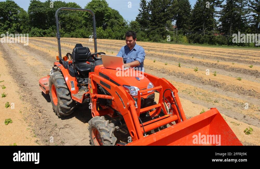 Farmer with laptop computer by tractor Stock Video Footage - Alamy