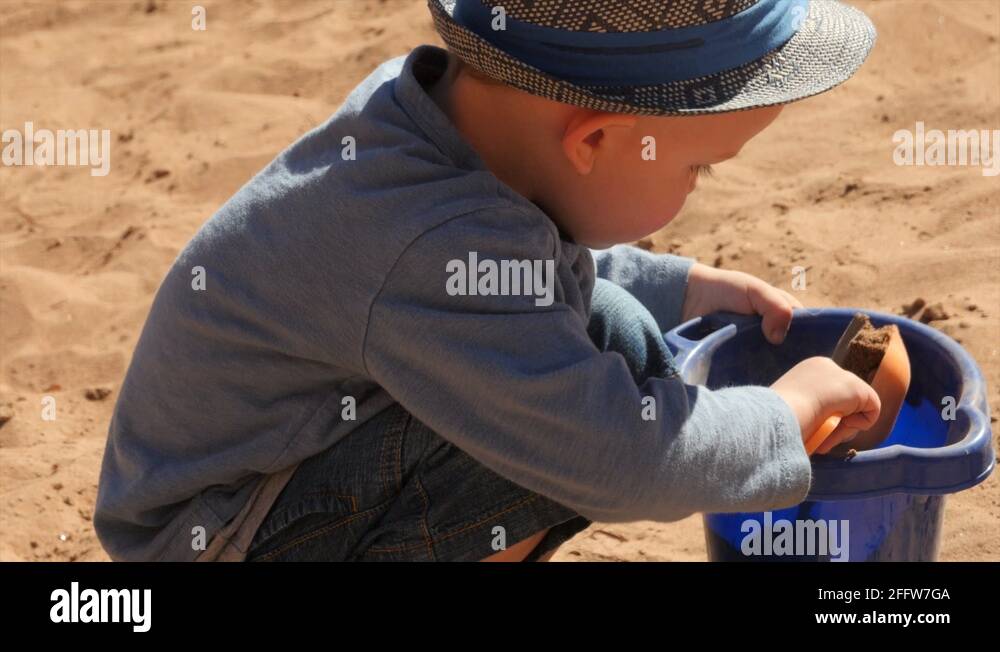 A cute boy filling bucket with sand on beach Stock Video Footage - Alamy