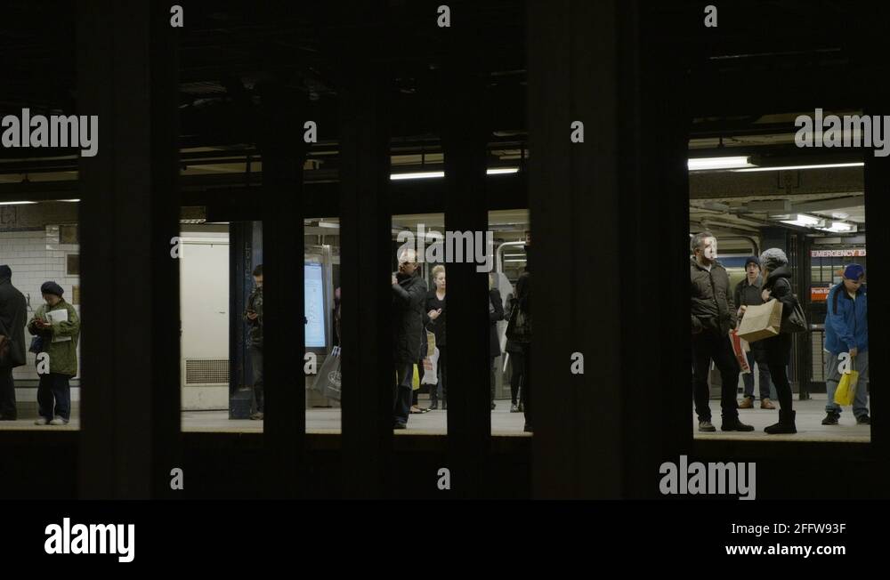 people waiting on MTA subway platform, seen from other side of tracks ...