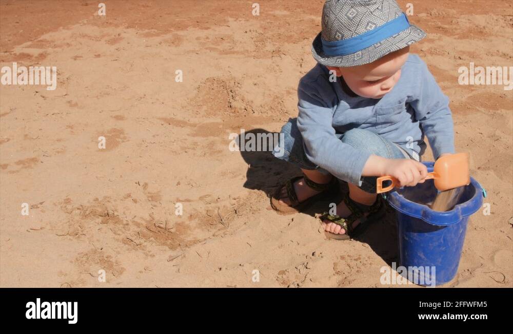 Cute boy filling bucket with sand on beach Stock Video Footage - Alamy