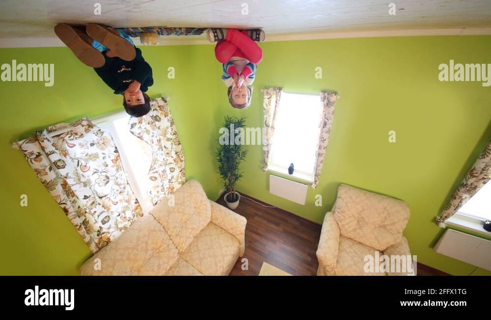 Two children upside down sit on ceiling in room of inverted house Stock ...