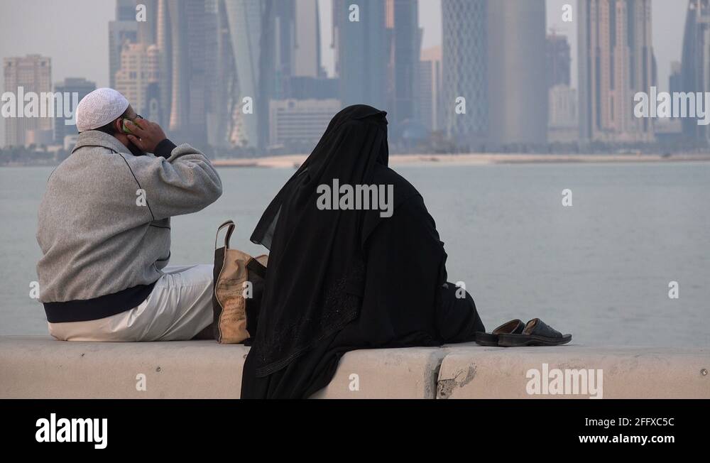 Doha, Qatar, a Muslim couple watch over citys skyline, mobile phone ...