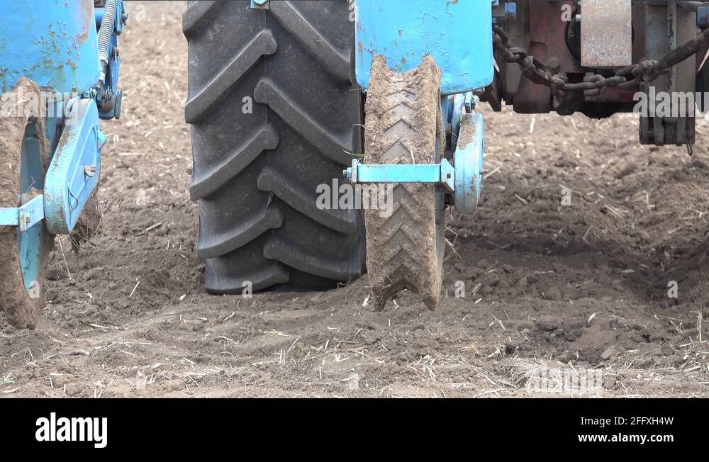Tractor is processing earth on background of homes, plow land ...
